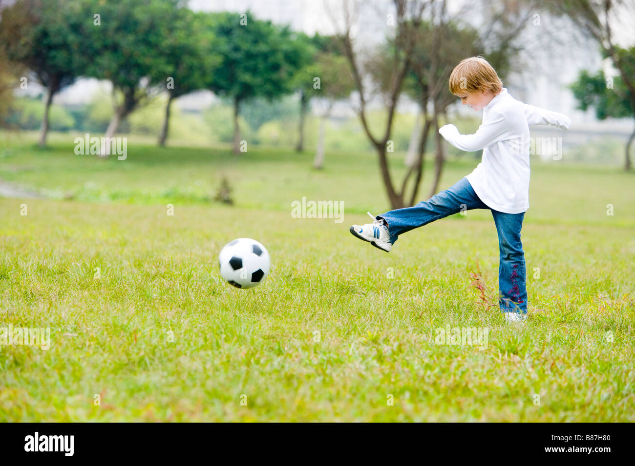 Boy kicking soccer on the lawn side view Stock Photo - Alamy