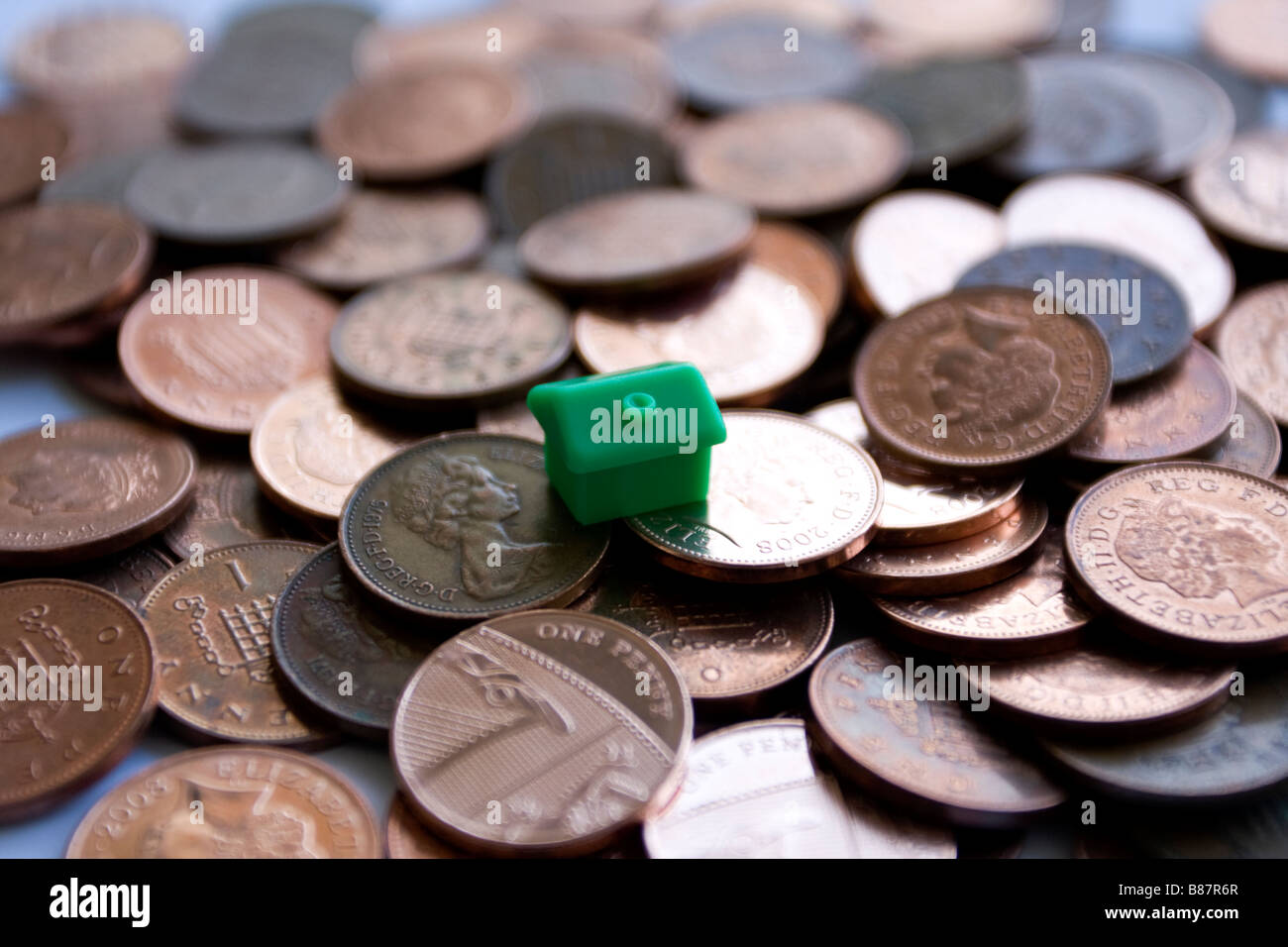lots of pennies and a monopoly house Stock Photo - Alamy