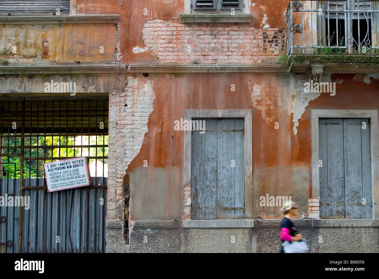 A woman walking down the street in front of a run down building in ...
