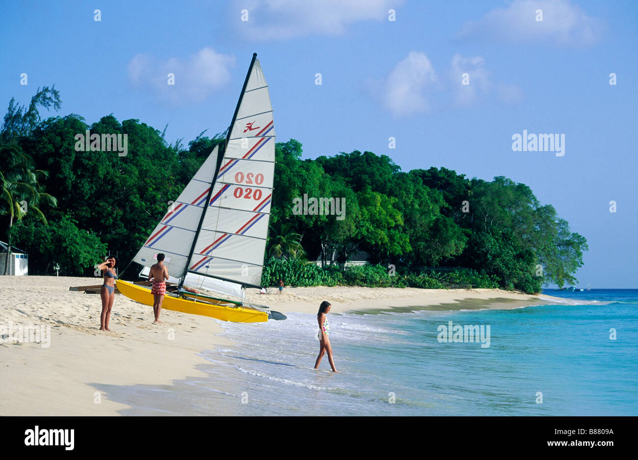 Sandy beaches. People on beach and paddling in sea. Sail boats on shore ...