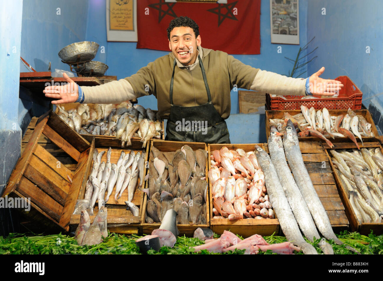 The salesman is laughing and showing his fish at his market stand ...