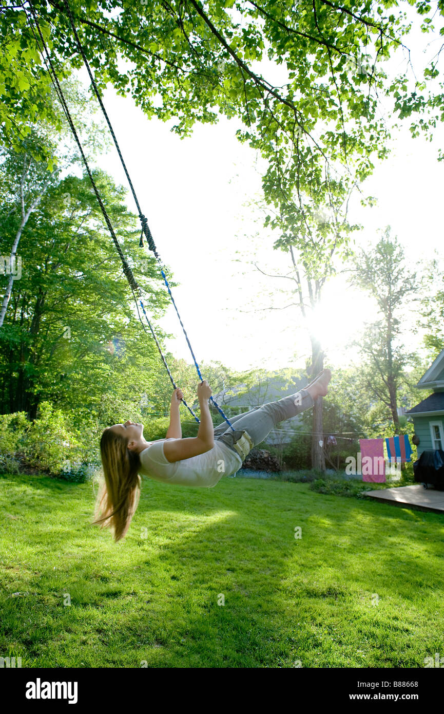 A young girl swings on a rope swing in her backyard Stock Photo - Alamy