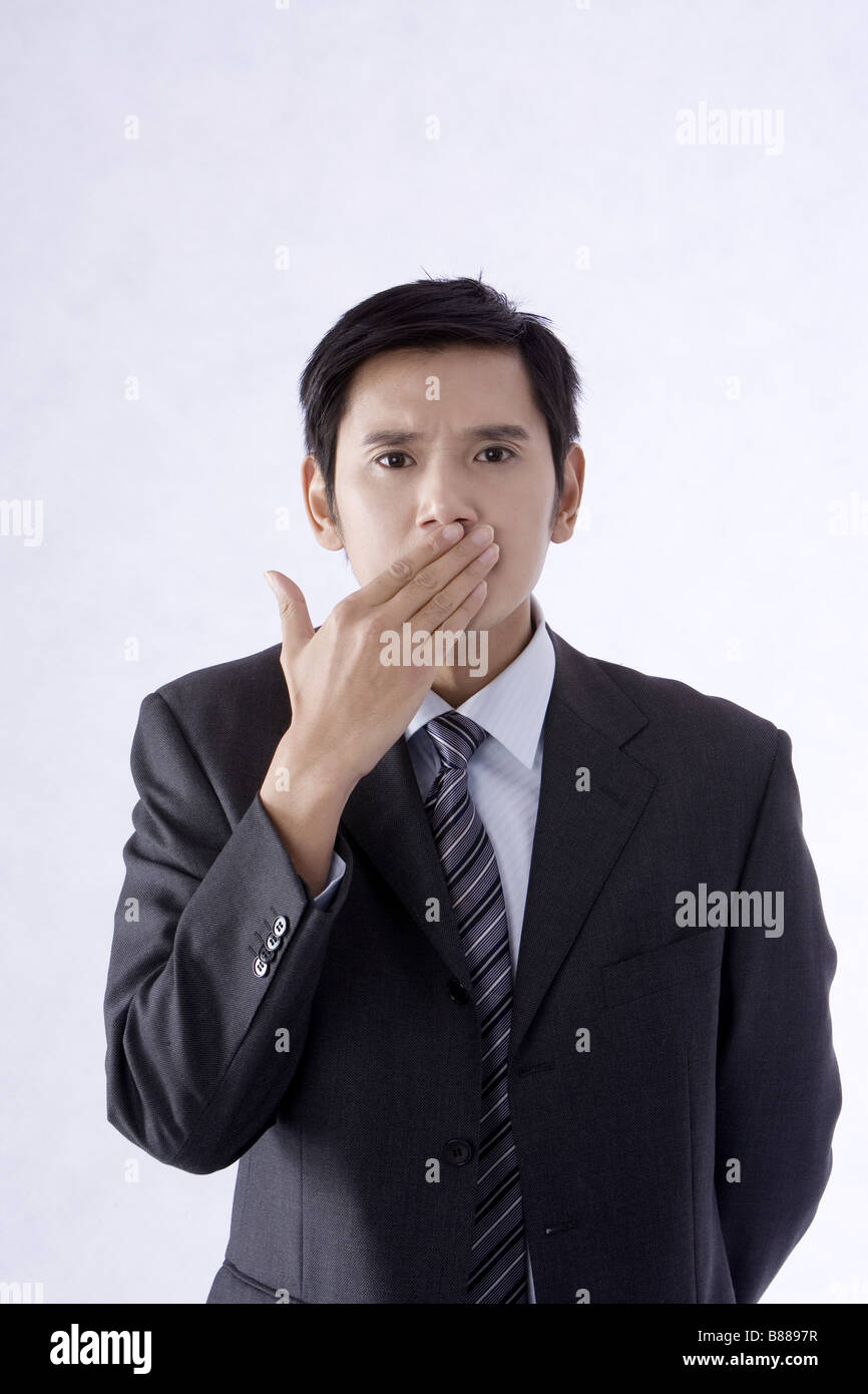 Young businessman with hand covering mouth portrait Stock Photo - Alamy