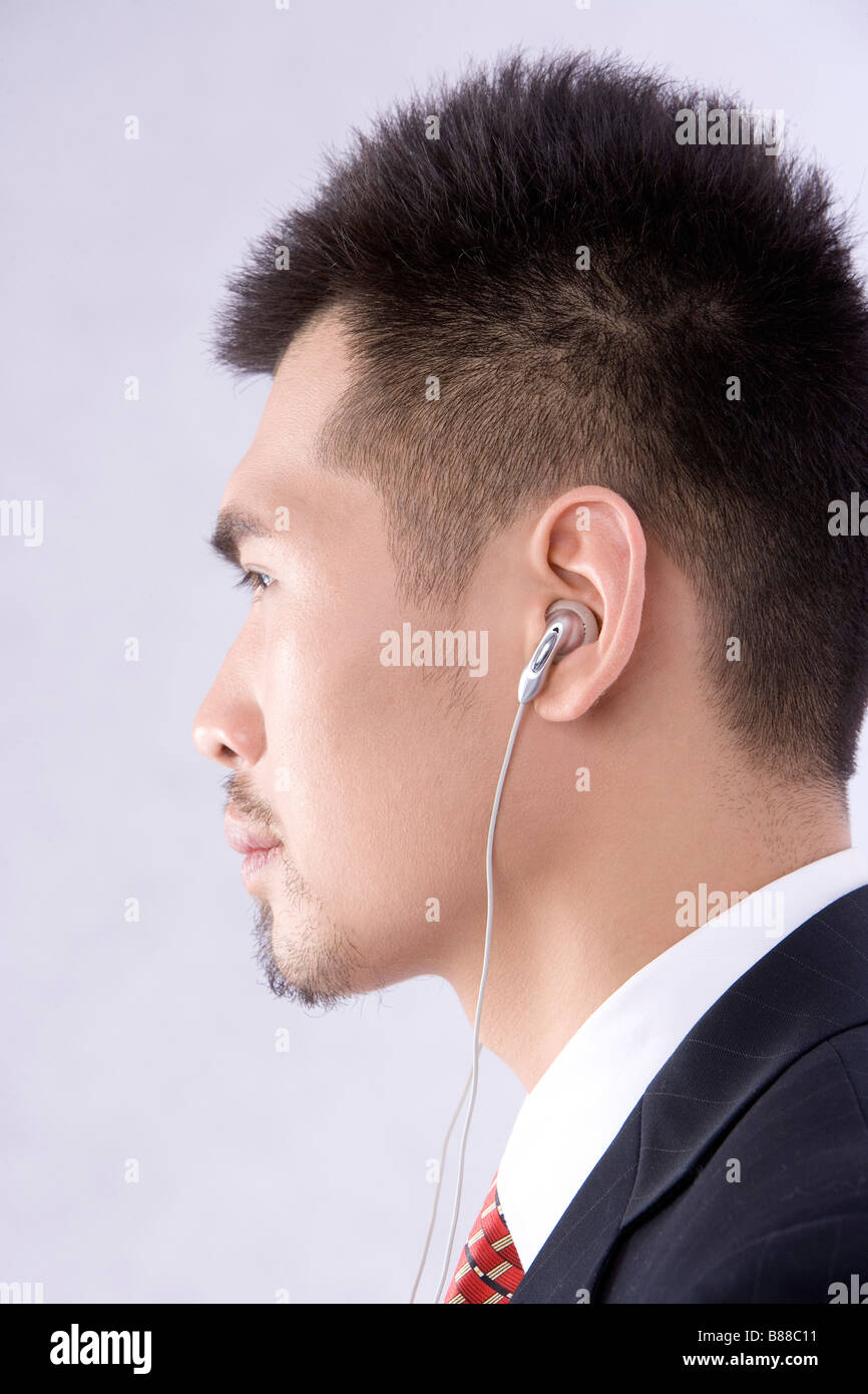 Young businessman using headphones side view Stock Photo - Alamy