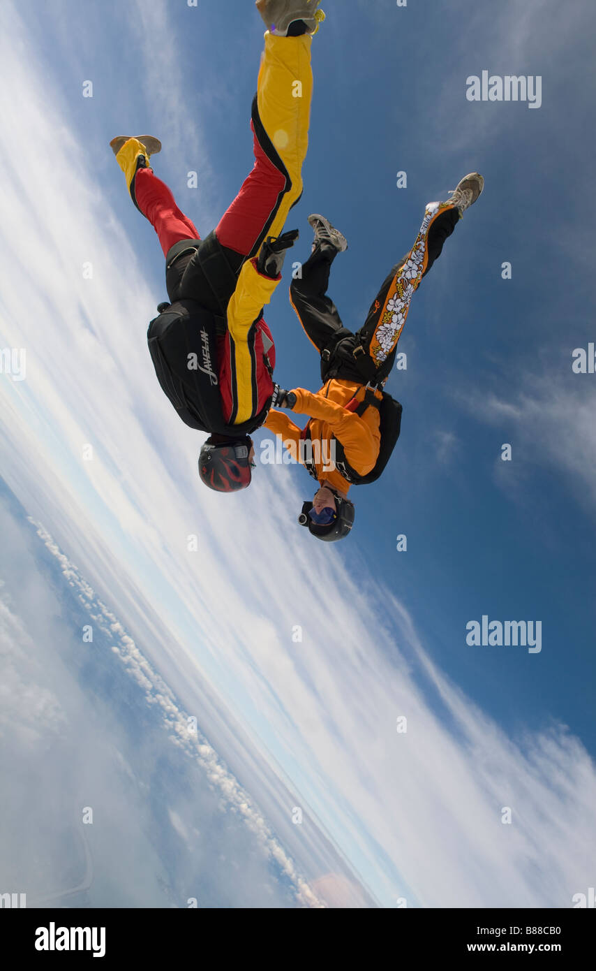Skydivers are flying head down and holding each other. In this freefly ...