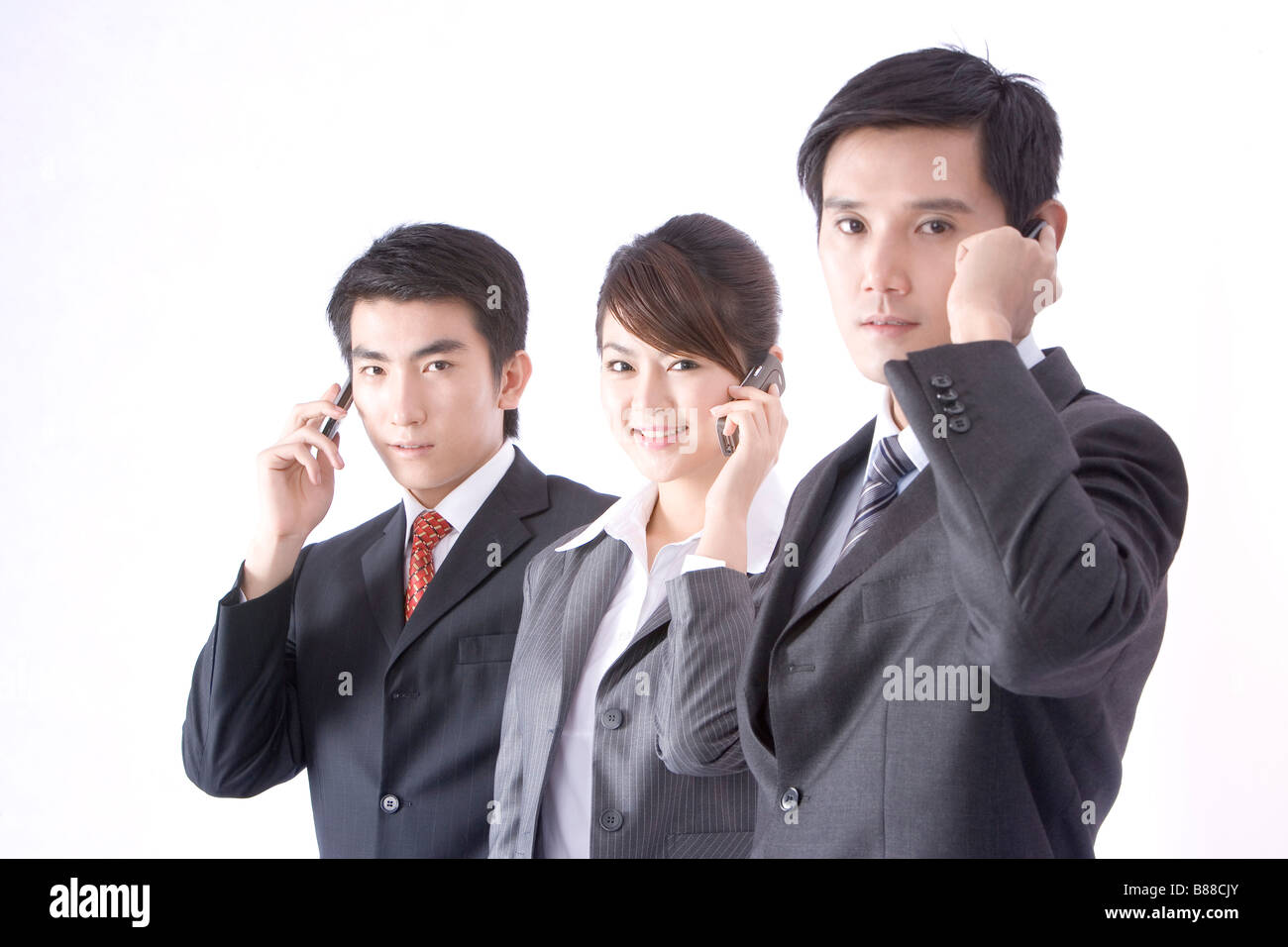 Three business people talking on their mobile phone side by side ...