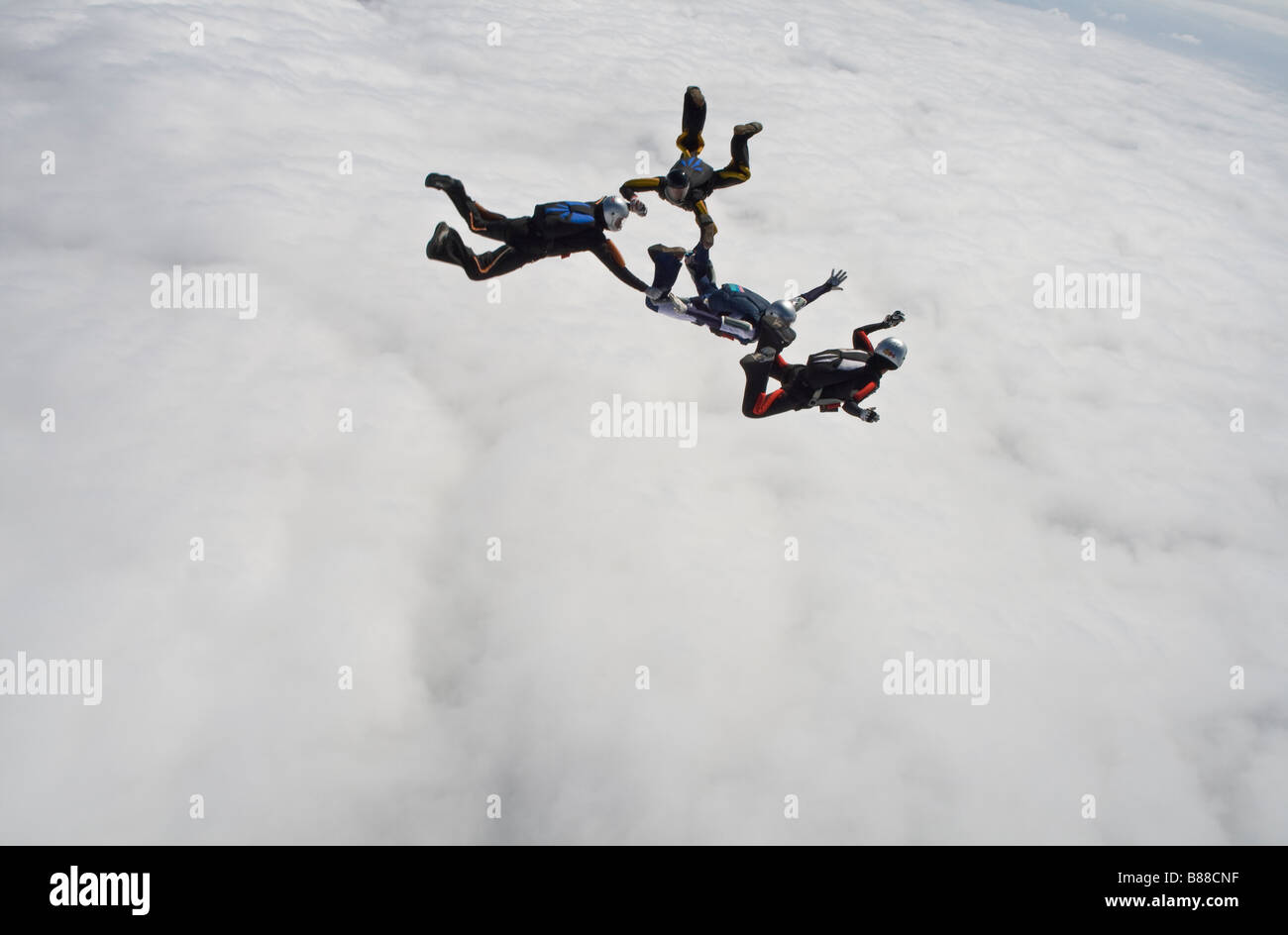 Skydiver team is flying a fomation in the sky over clouds. 4-way ...