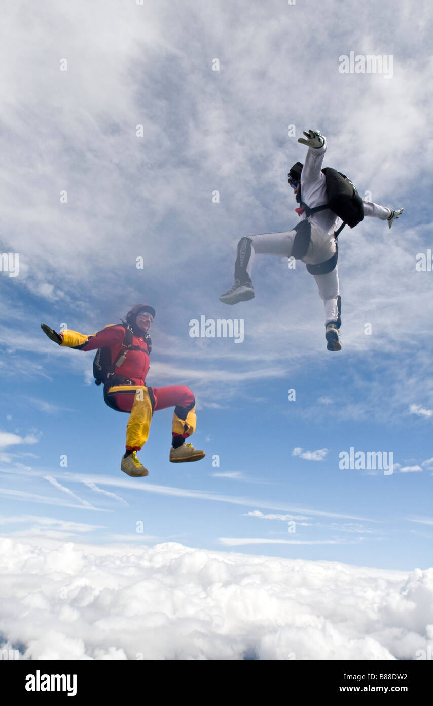 Skydivers are falling in the sit position above clouds and flying ...