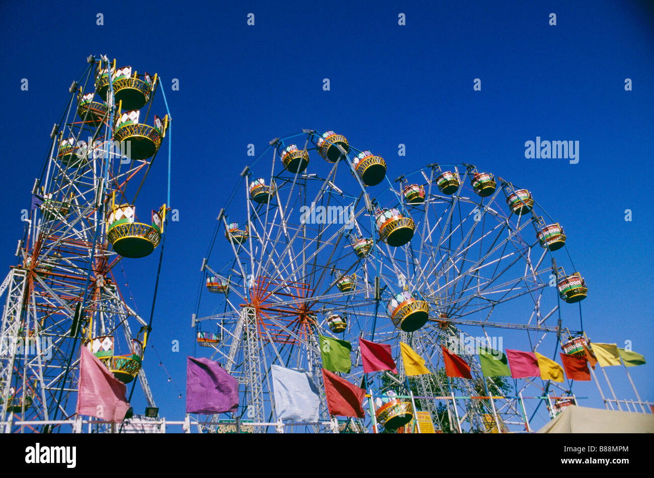 Ferris wheels funfair Brightly coloured gondolas cabins against blue ...
