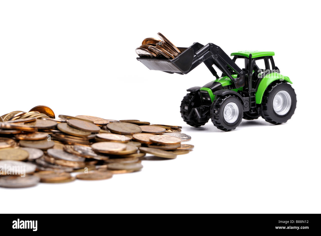 Green tractor raking up coins white background Stock Photo - Alamy