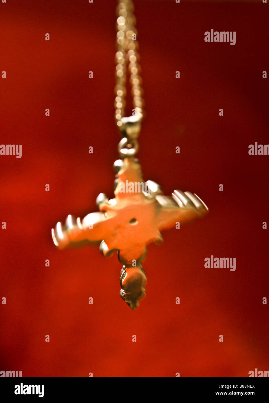 A holy cross on a chain is spinning against a backround of red Stock ...