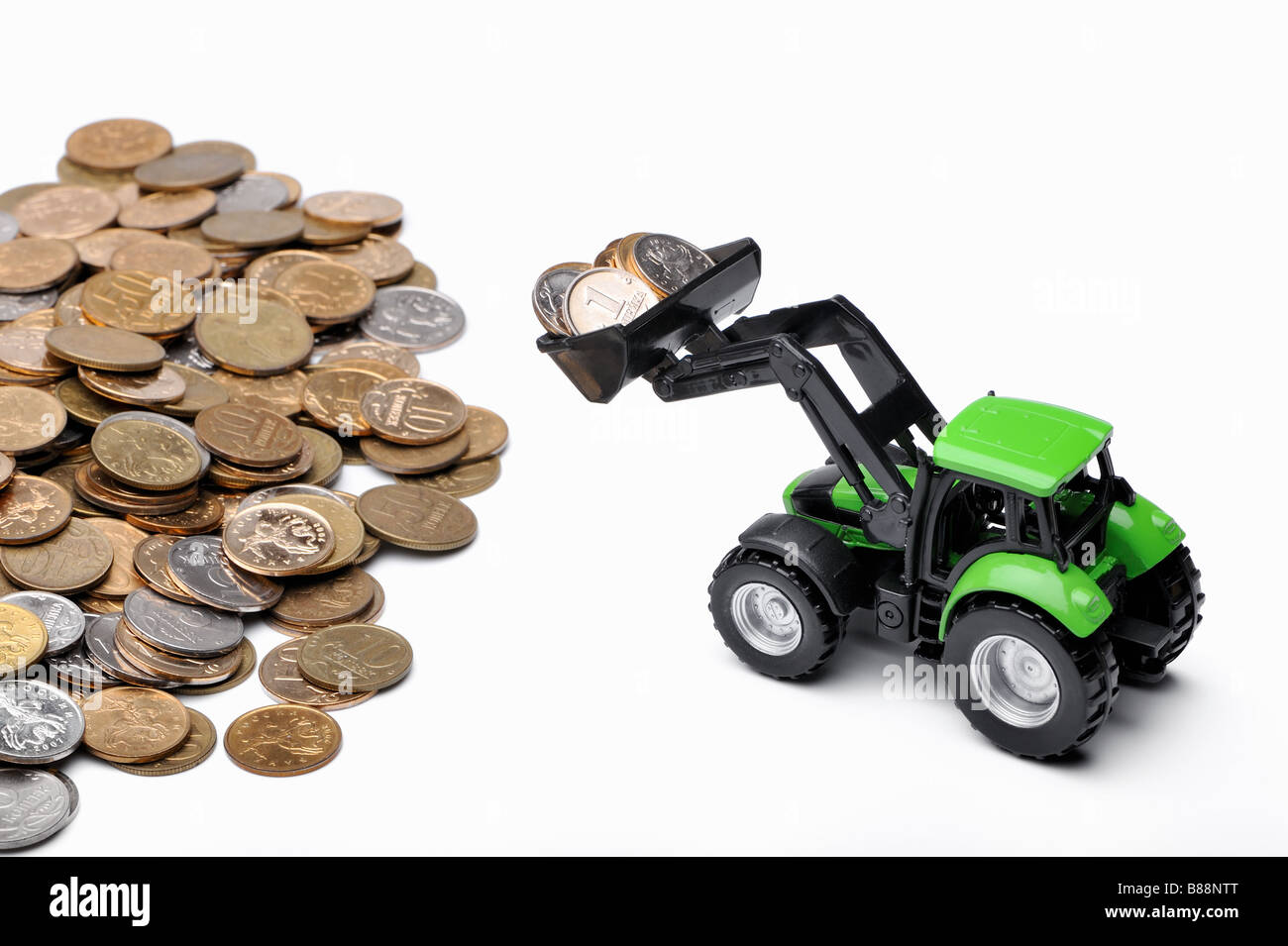 Green tractor raking up coins white background Stock Photo - Alamy