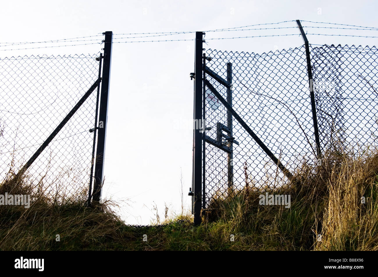 Wire security fence and open gate Stock Photo - Alamy