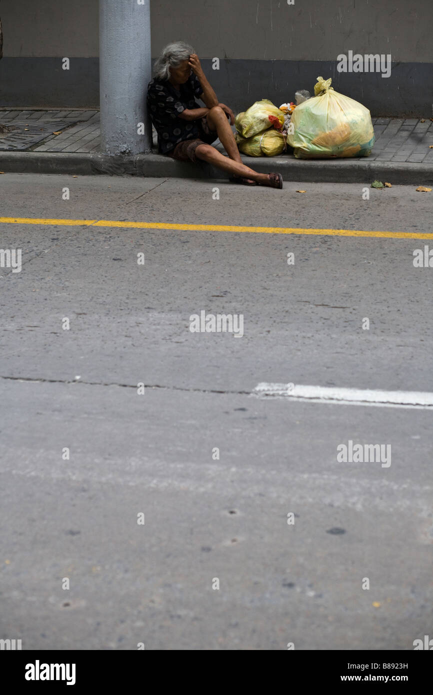 Homeless woman in Shanghai rests on sidewalk after searching garbage ...