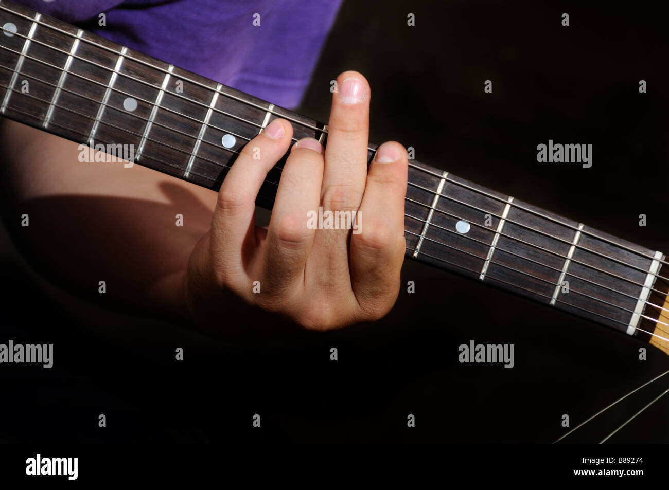 Detail of male hands doing a musical chord on electric guitar fretboard ...