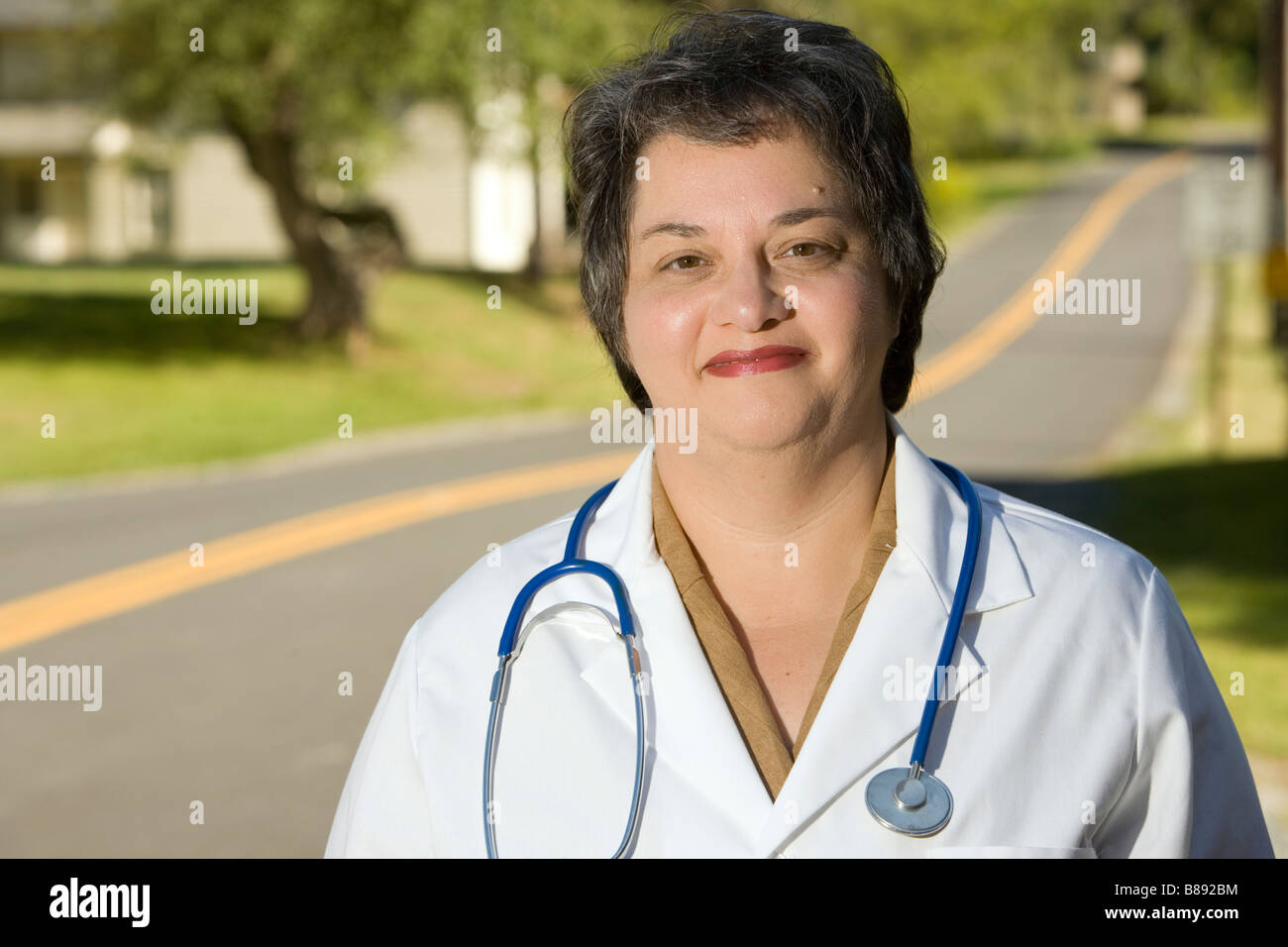 Middle aged female doctor stands on a deserted country road in a rural ...