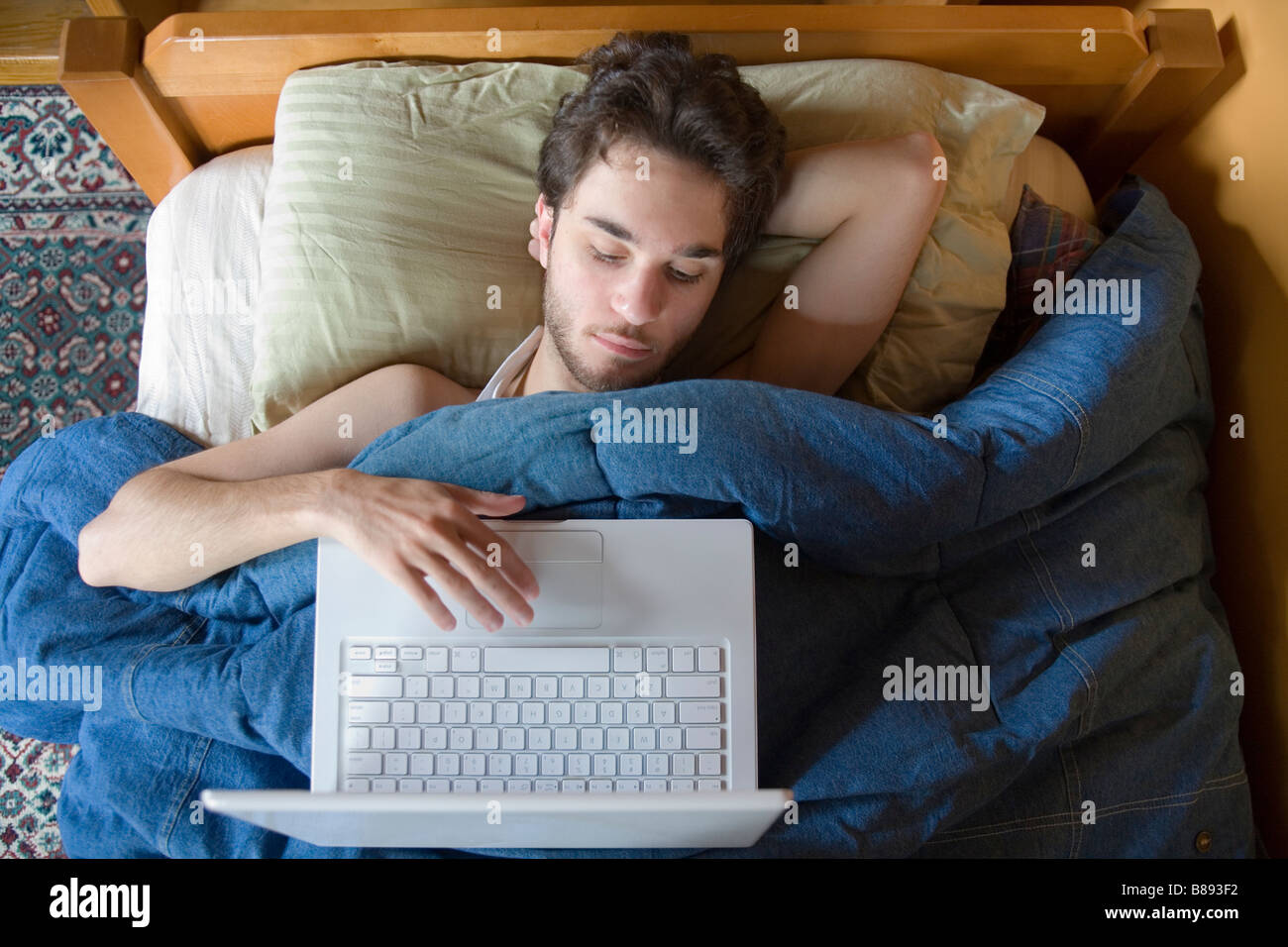 A young man using his laptop computer while still lying in bed Stock ...