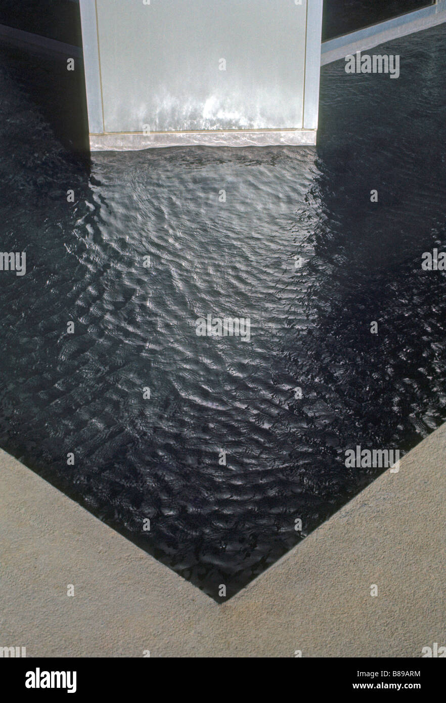 Water ripples in shallow pond soften hard lines of modern building ...