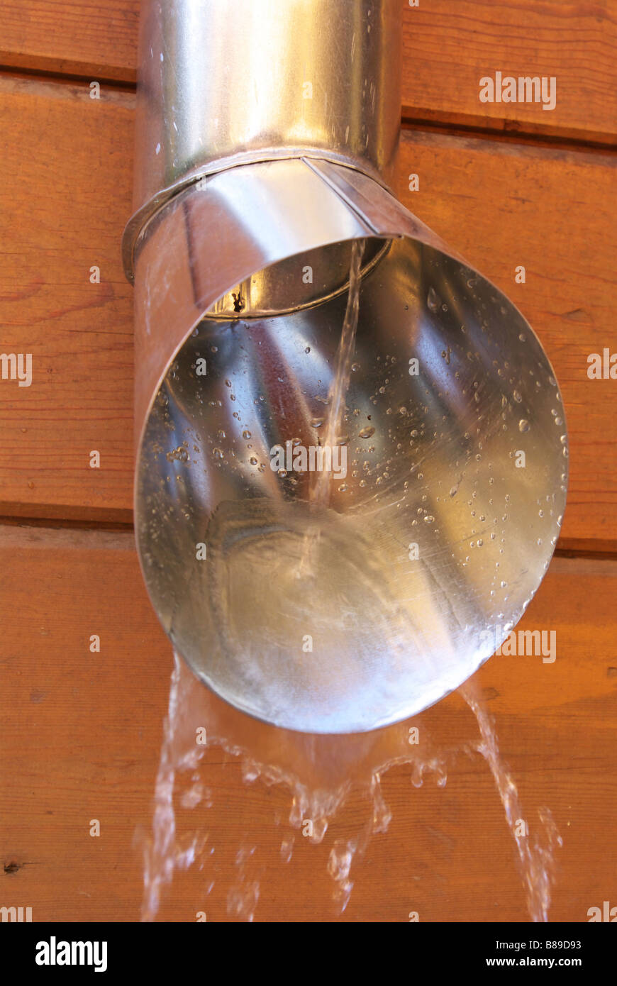 Water flow from the drainpipe installed on the wooden wall Stock Photo ...