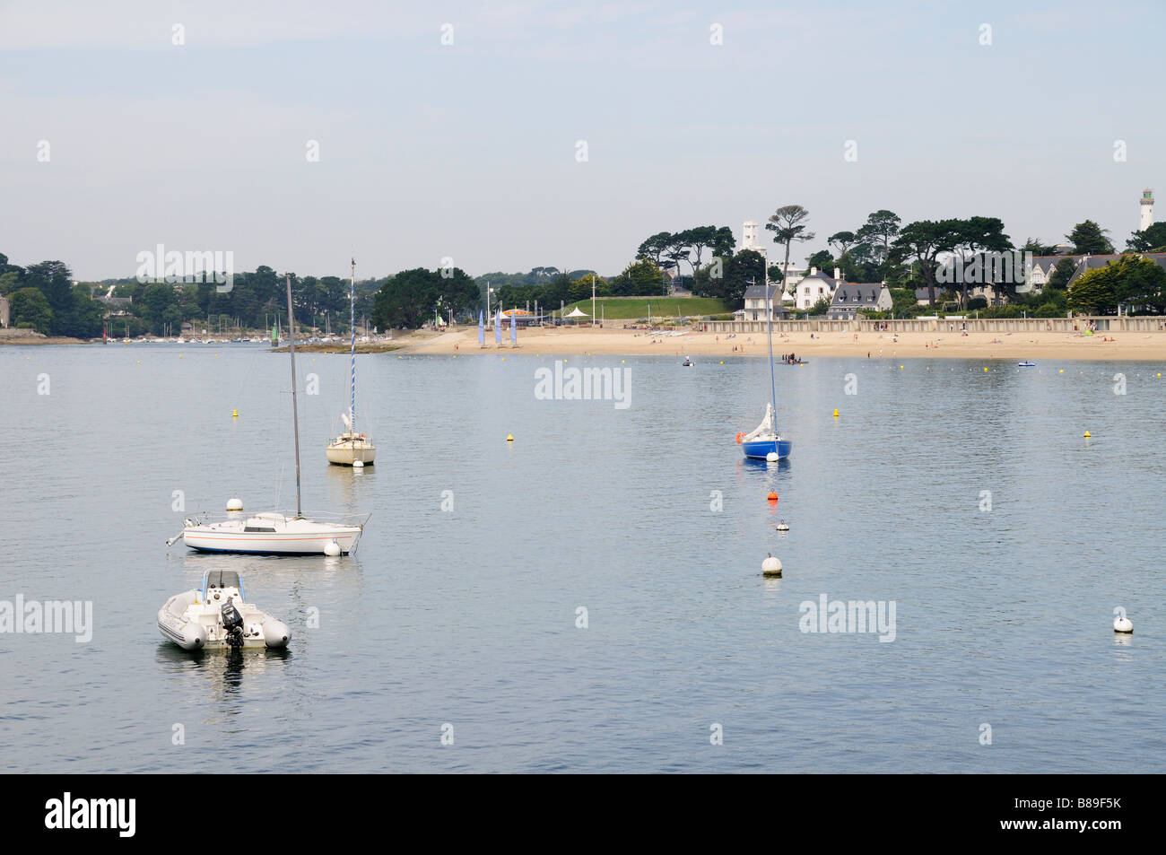 Yachts anchored in a quiet bay in front of the beach at Benodet on a ...