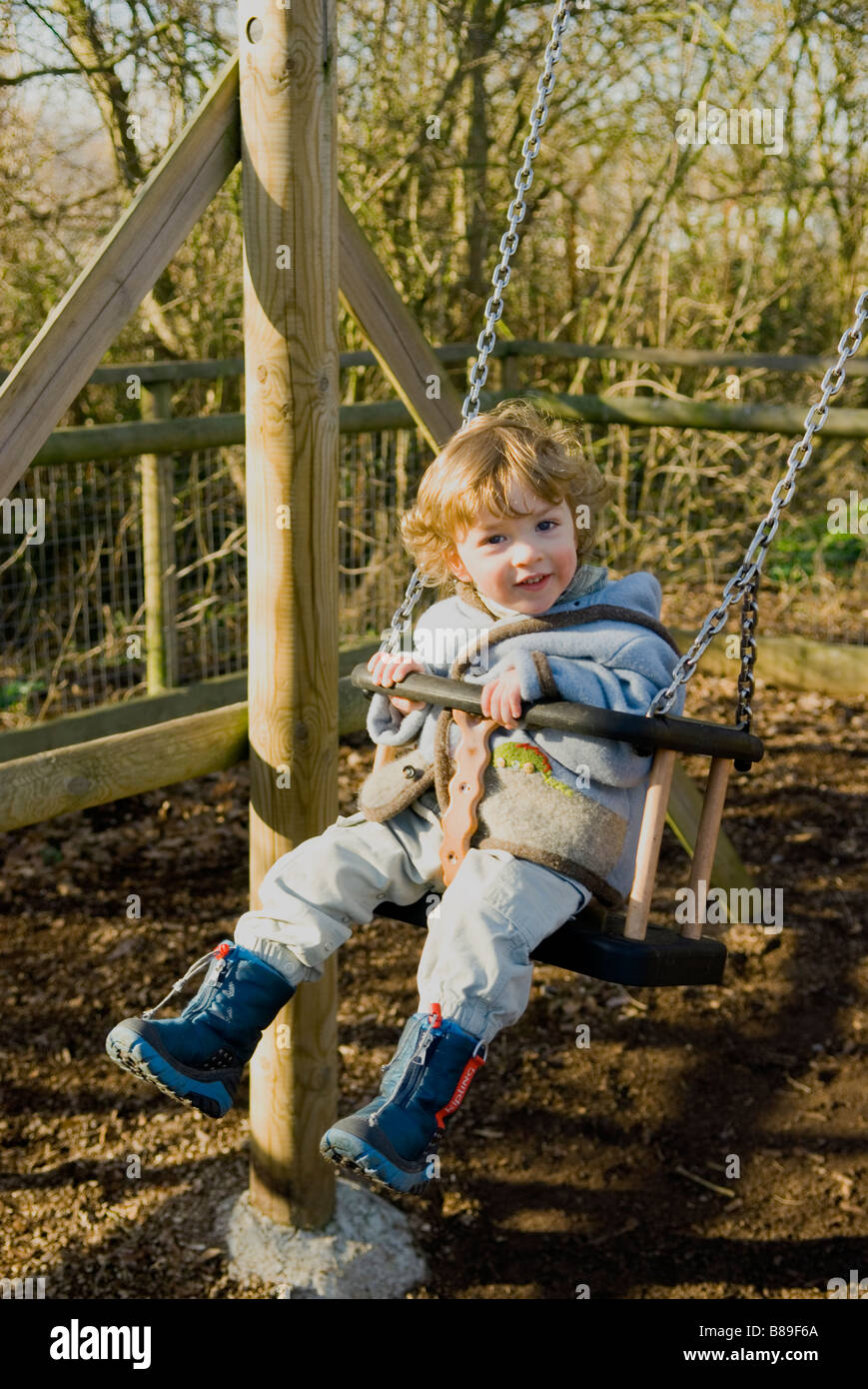 Young boy playing on swing Stock Photo - Alamy