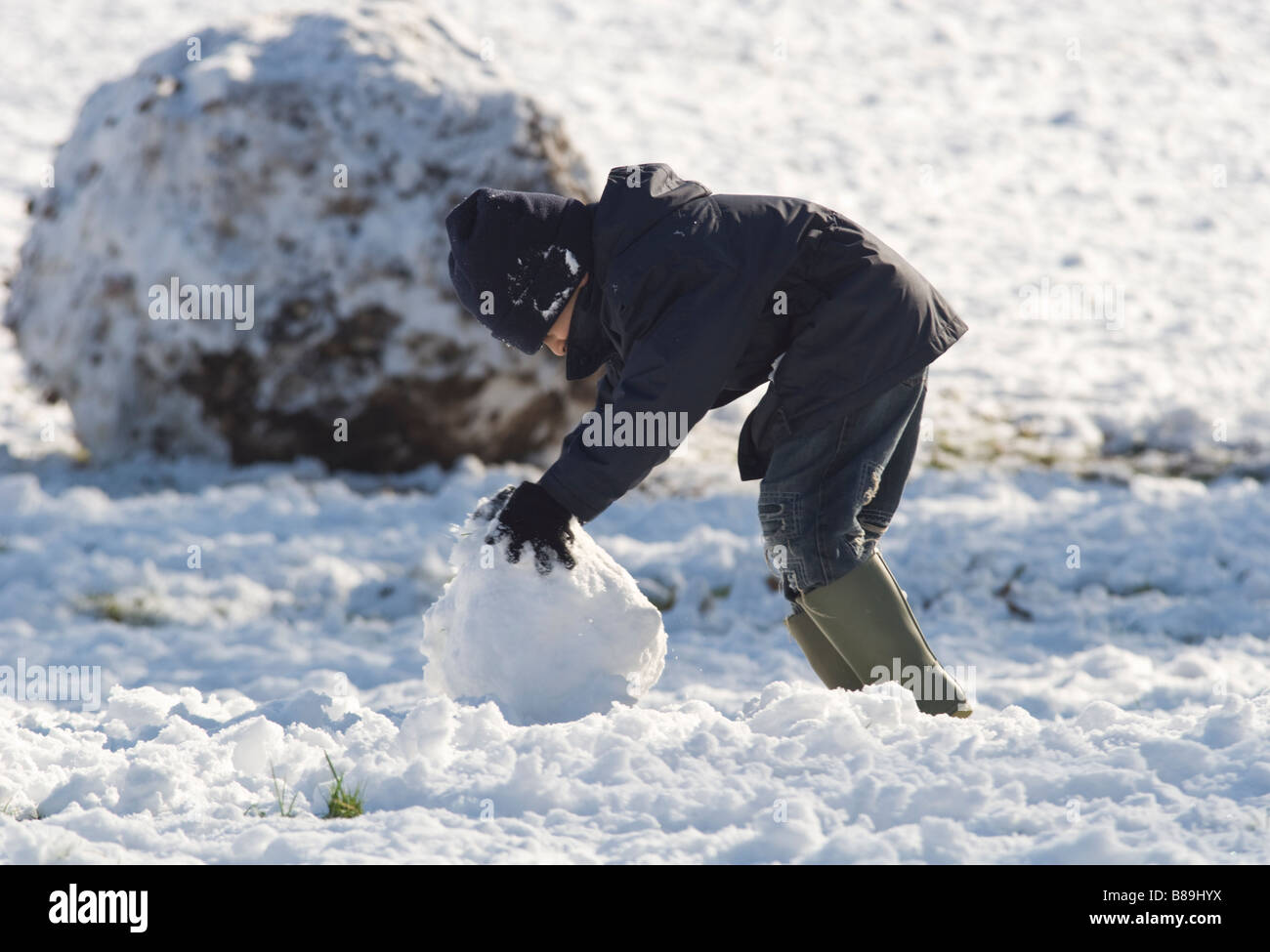 Boy making snowman Stock Photo - Alamy