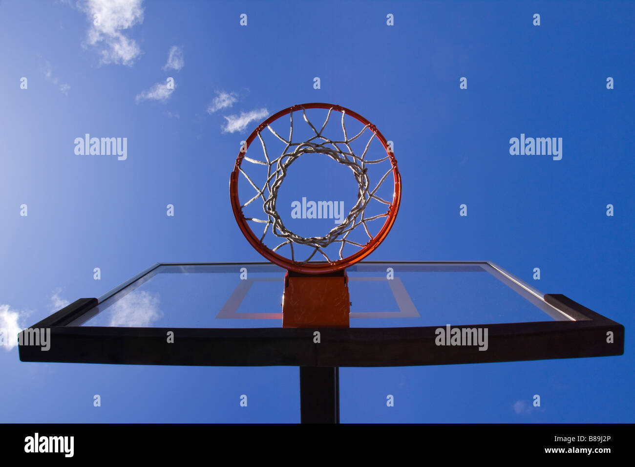 Basketball hoop net and backboard directly overhead with clouds and ...