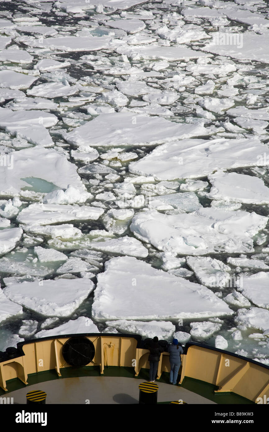 2 passengers watching big floating pancake ice from bow deck of ...