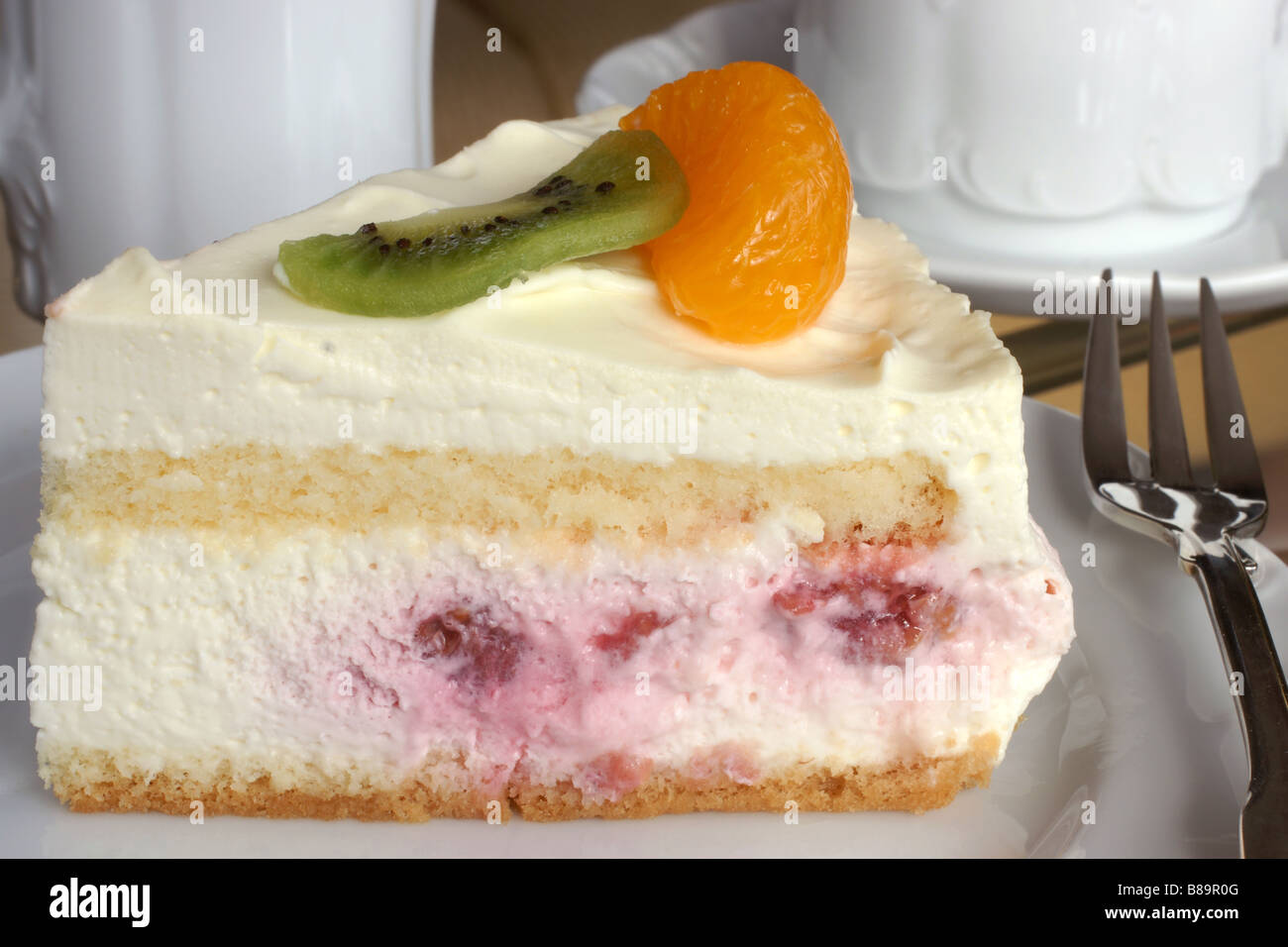 Fresh fruit torte on a plate with a silver cake fork cup and milk jug ...