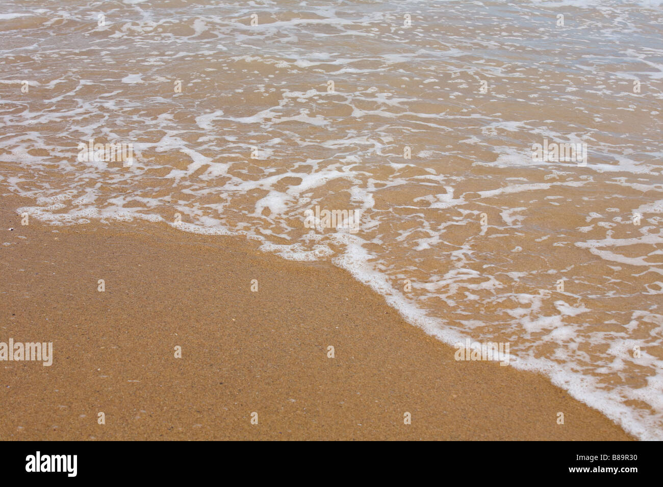 Wave of the sea on the wet sand Stock Photo - Alamy