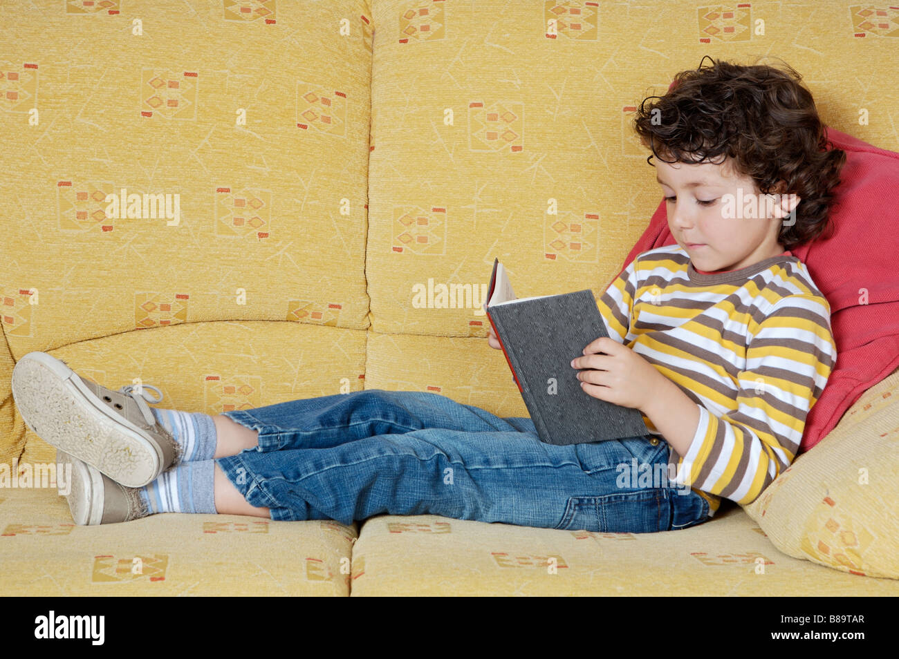 adorable happy boy reading in the armchair of your house Stock Photo ...