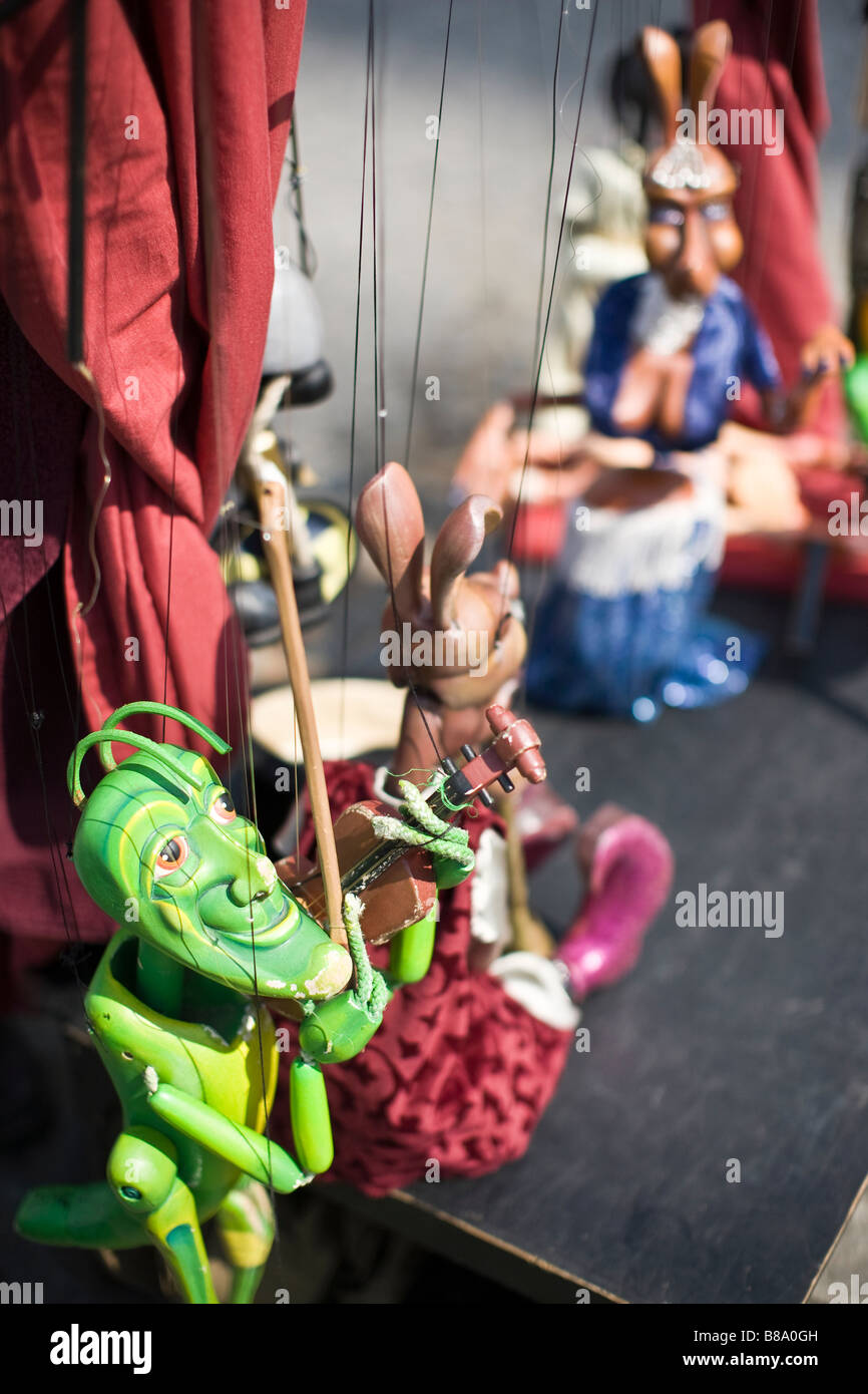 A green wooden grasshopper string puppet on display with other puppets ...