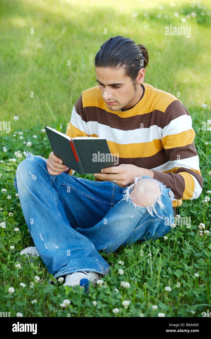 Casual boy reading a book in the green grass Stock Photo - Alamy