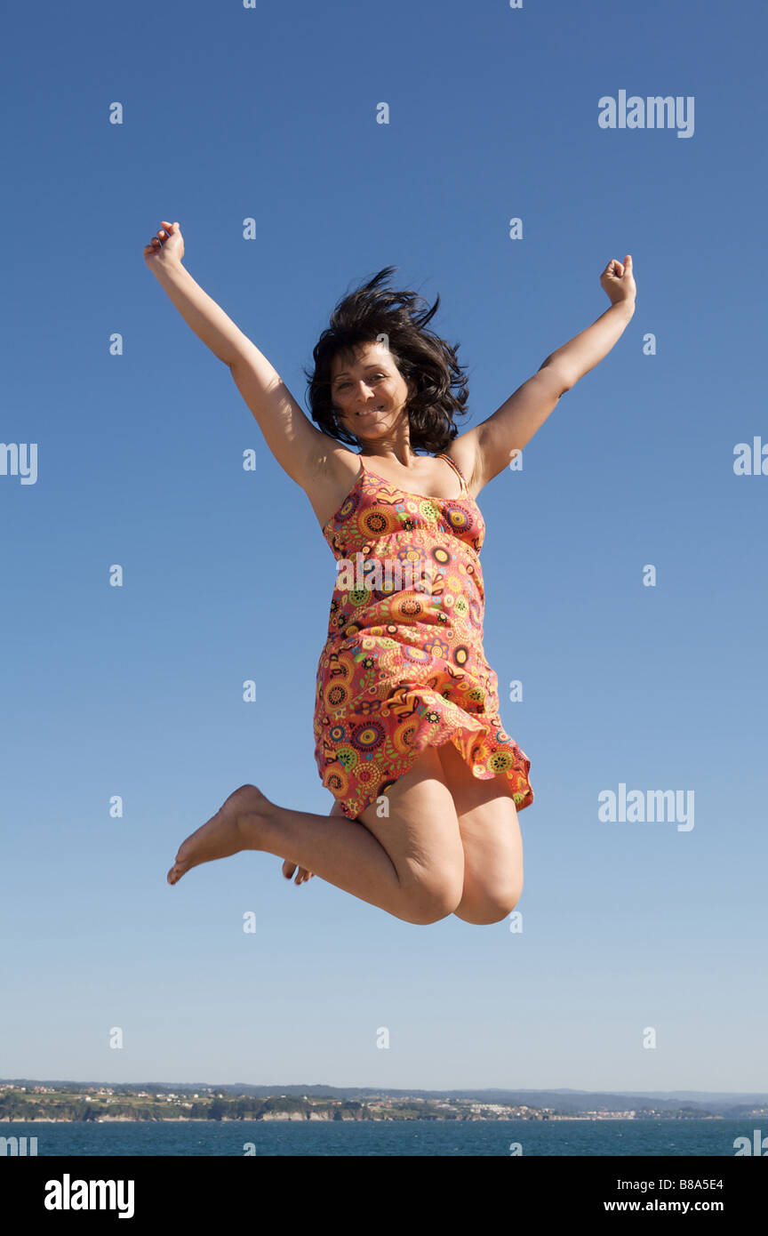 Beautiful girl jumping a over sky background Stock Photo - Alamy