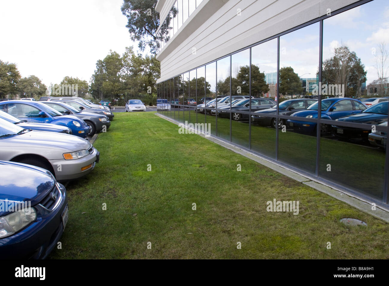 Row of cars parked at a modern office building reflecting in the ...