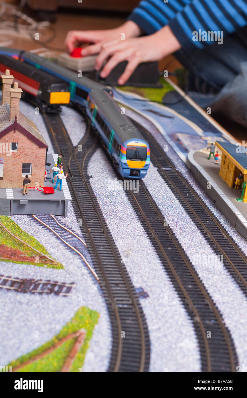 Young boy playing with a model toy electric train set in oo gauge with ...