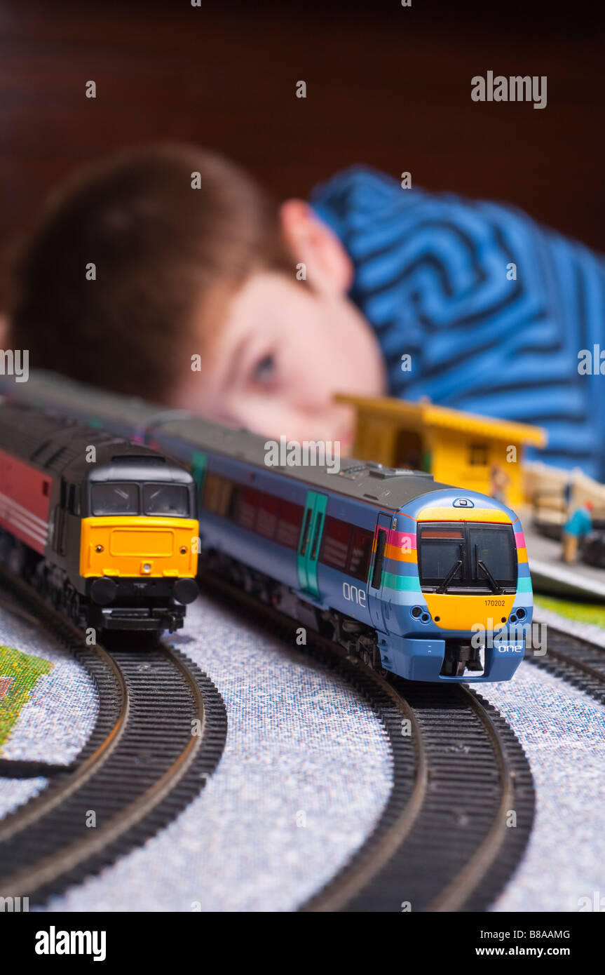 Young boy playing with a model toy electric train set in oo gauge with ...