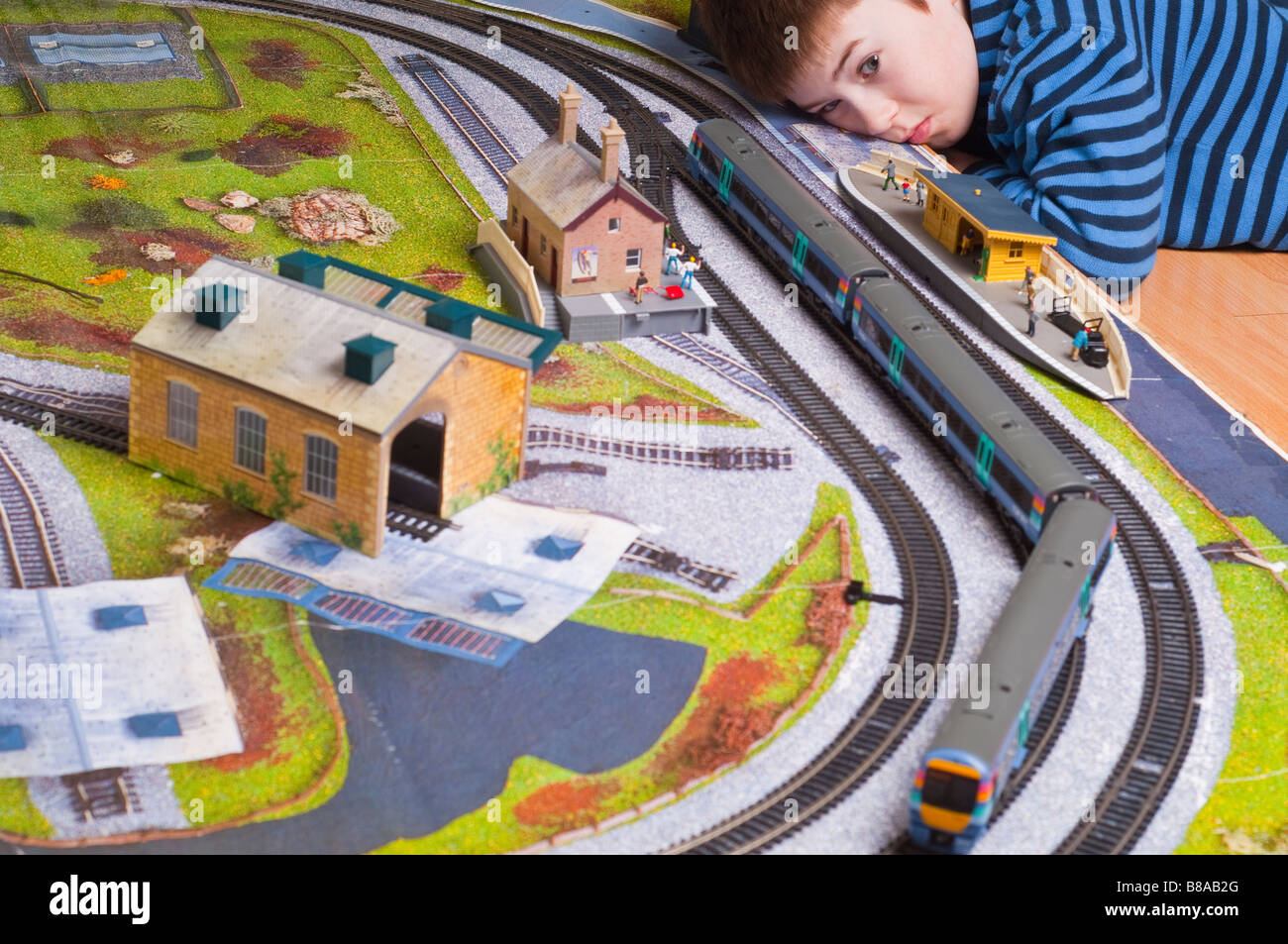 Young boy playing with a model toy electric train set in oo gauge with ...