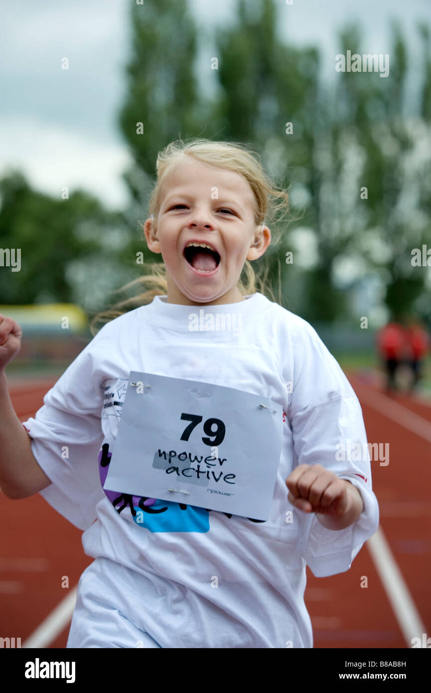 A girl wins a running race at an athetics meeting involving children ...