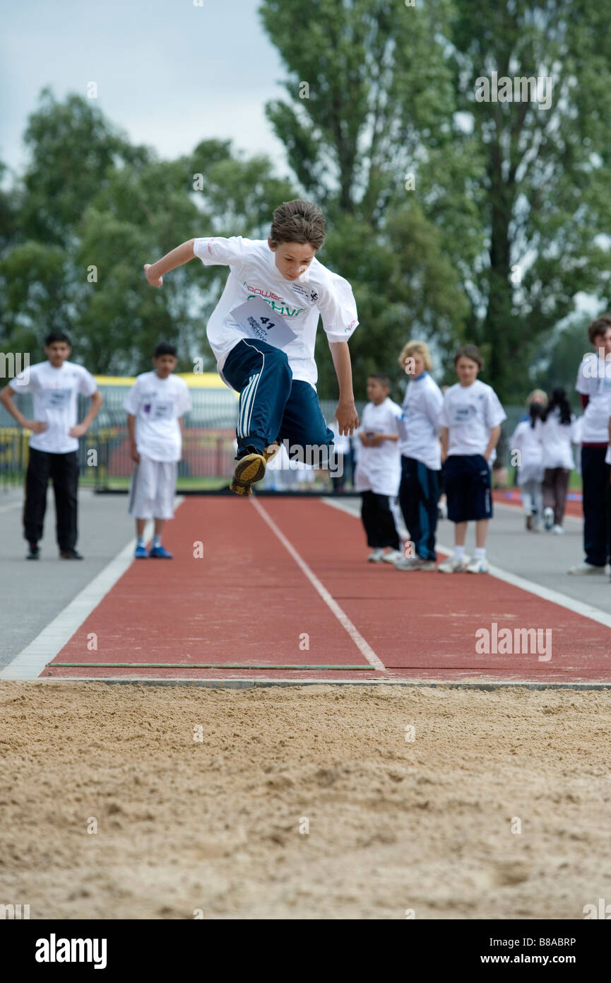 A boy takes part in the long jump at an athetics meeting involving ...