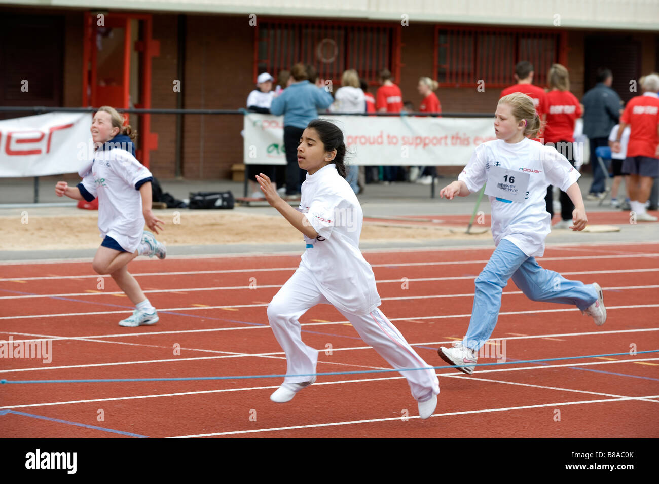 A young Asian girl races on an athetics track involving children with ...