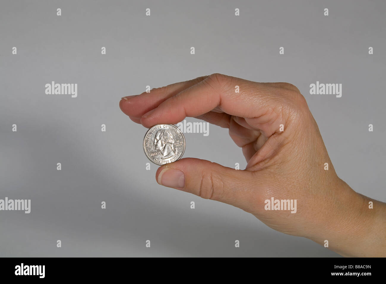 Someone holding an American US quarter or 25 cent piece with a picture ...