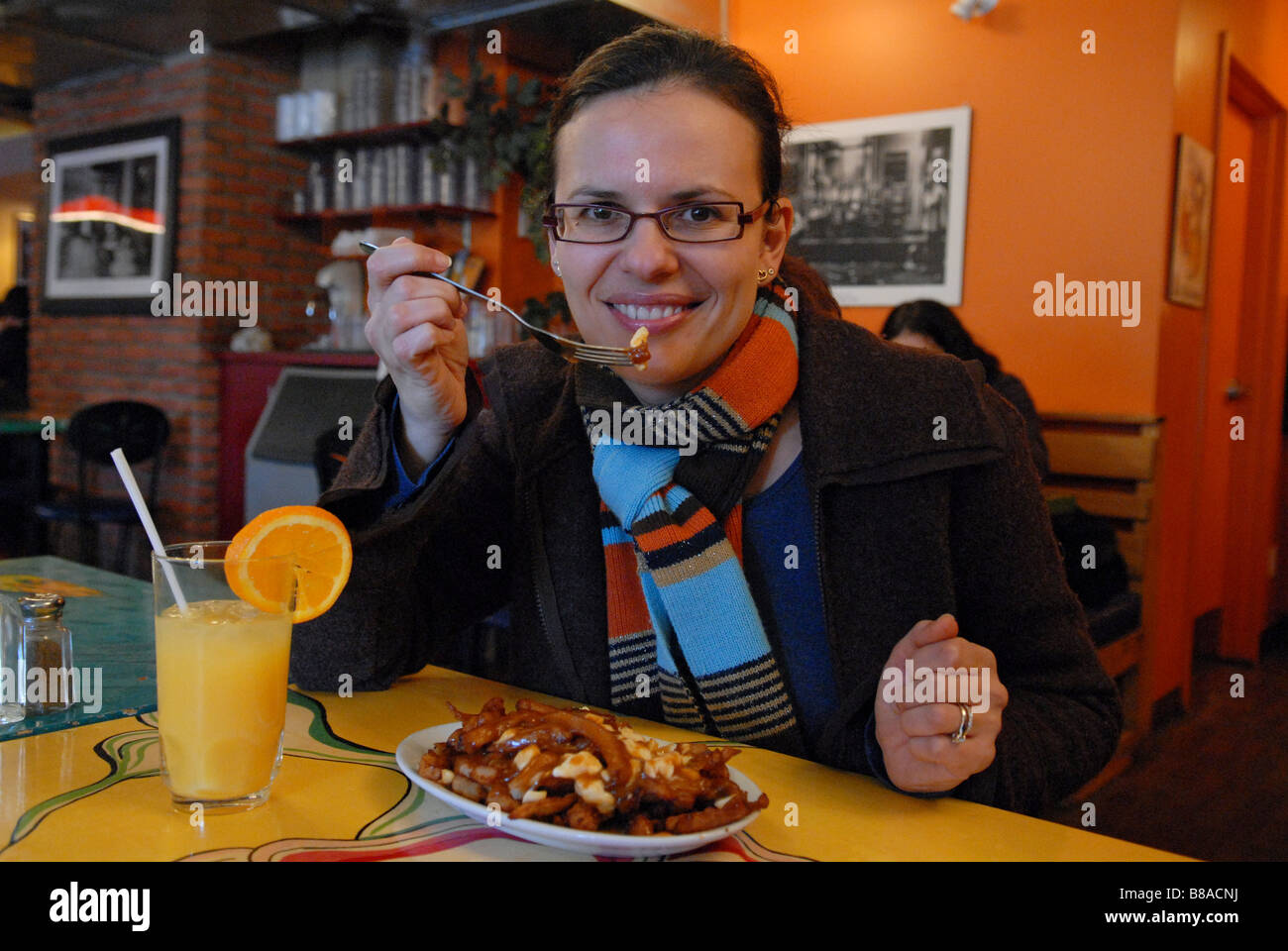Woman eating traditional poutine in La Banquise restaurant Montreal ...