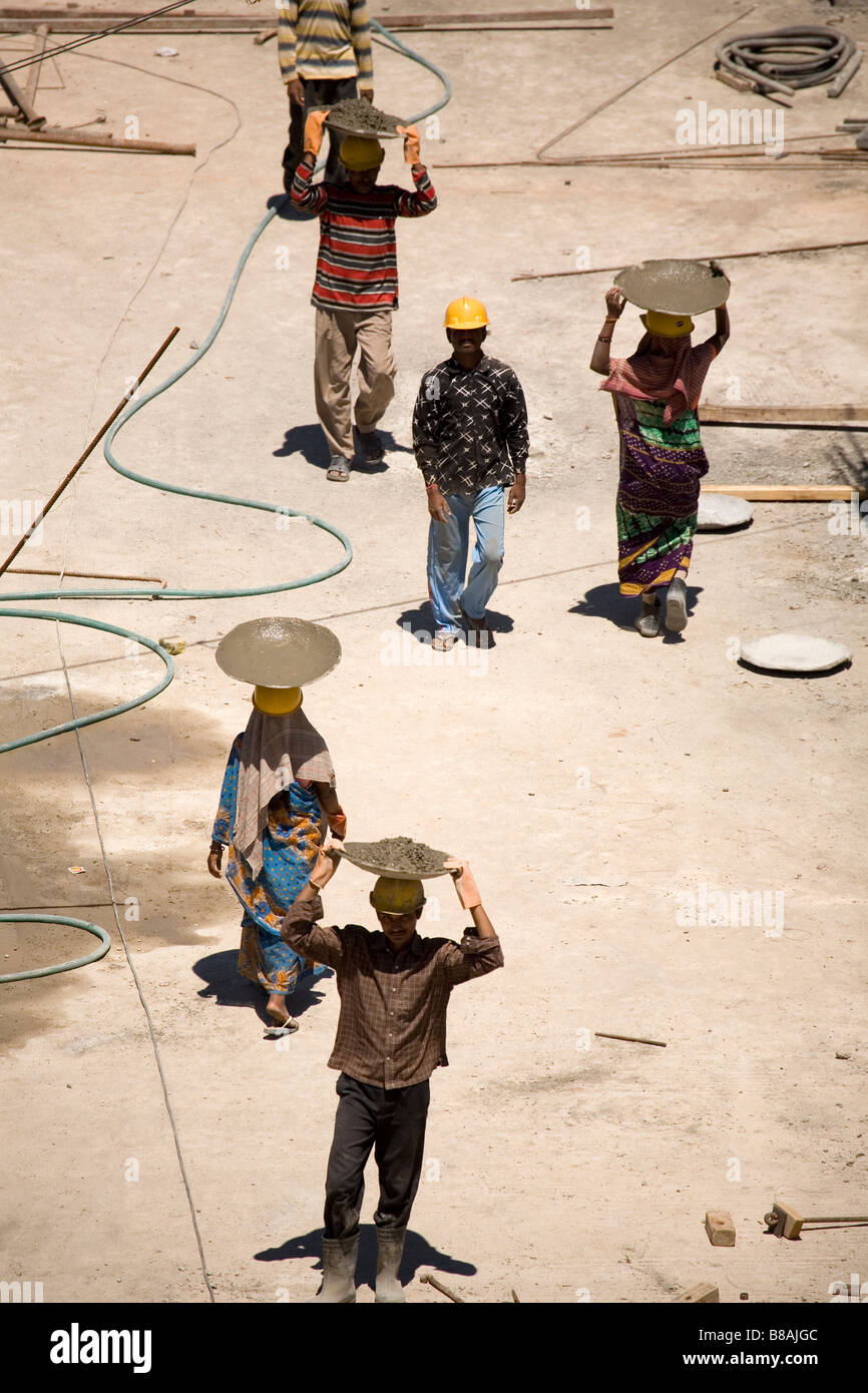 People carry concrete on their heads on a construction site in ...
