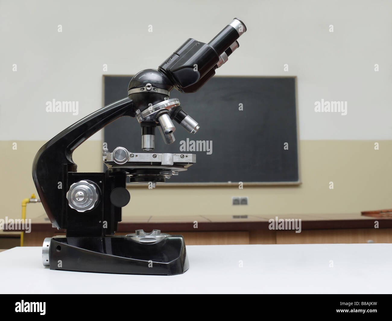 Old school microscope in classroom with blackbroard in the background ...