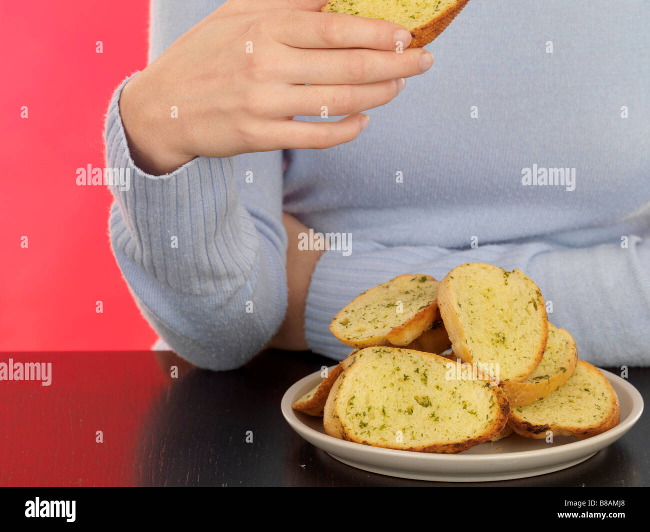 Young Woman Eating Freshly Cooked Italian Style Garlic Bread Against A ...