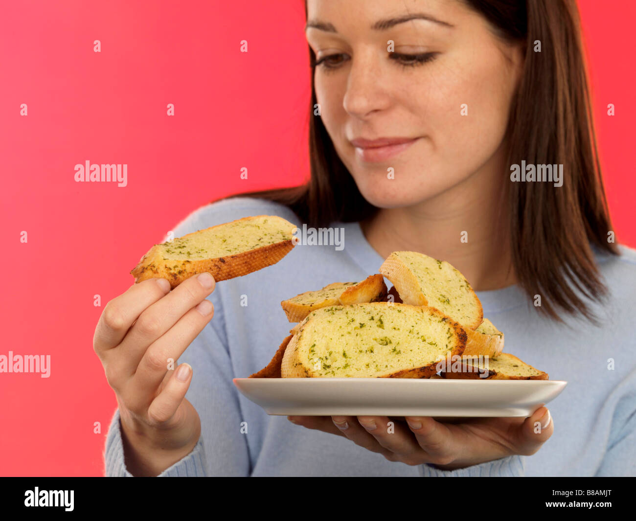 Young Woman Eating Freshly Cooked Italian Style Garlic Bread Against A ...