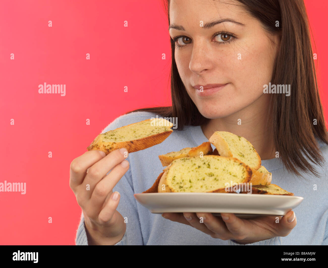 Young Woman Eating Freshly Cooked Italian Style Garlic Bread Against A ...
