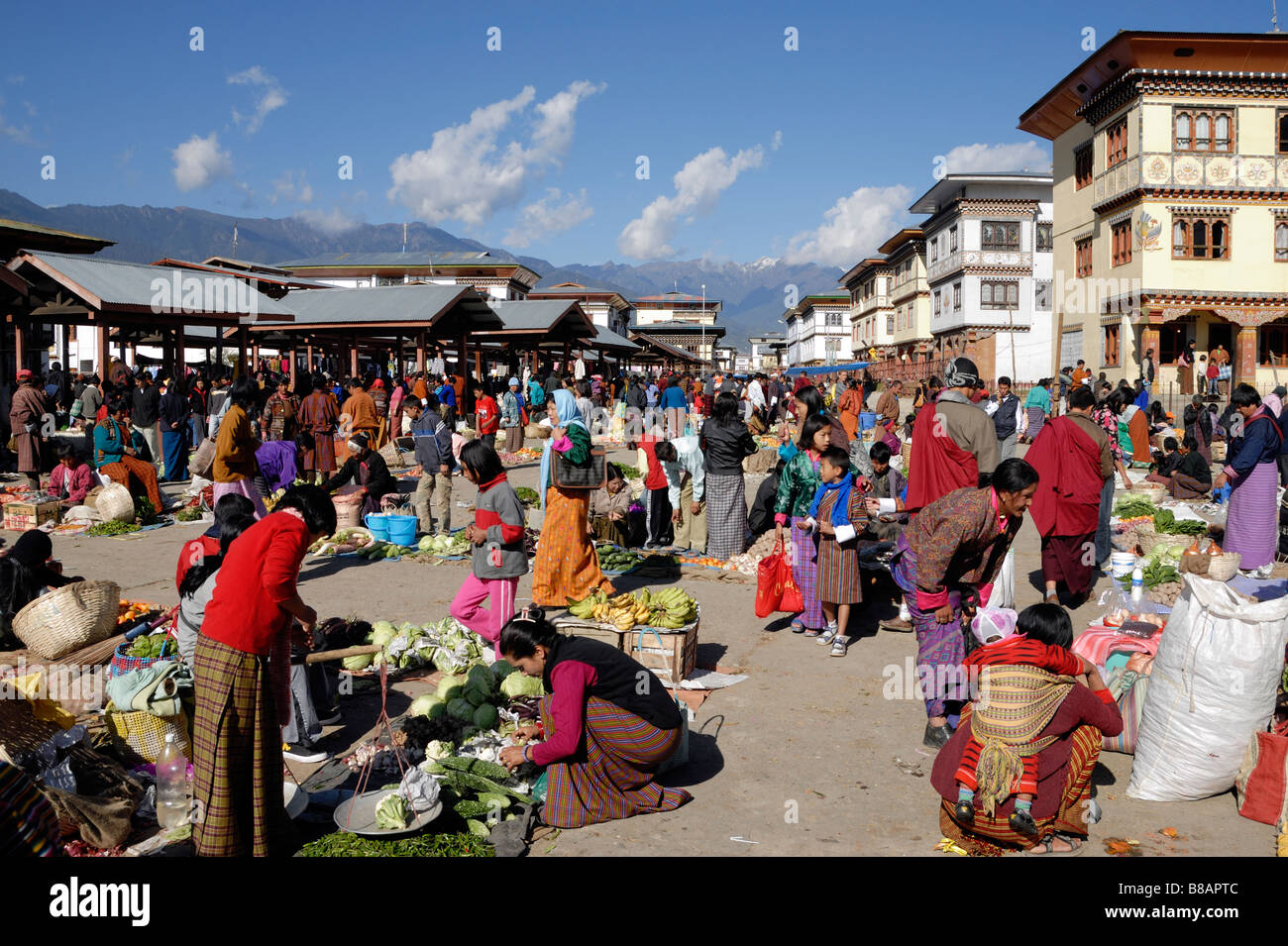 A crowd of people inspect goods on sale in the market square in Paro ...