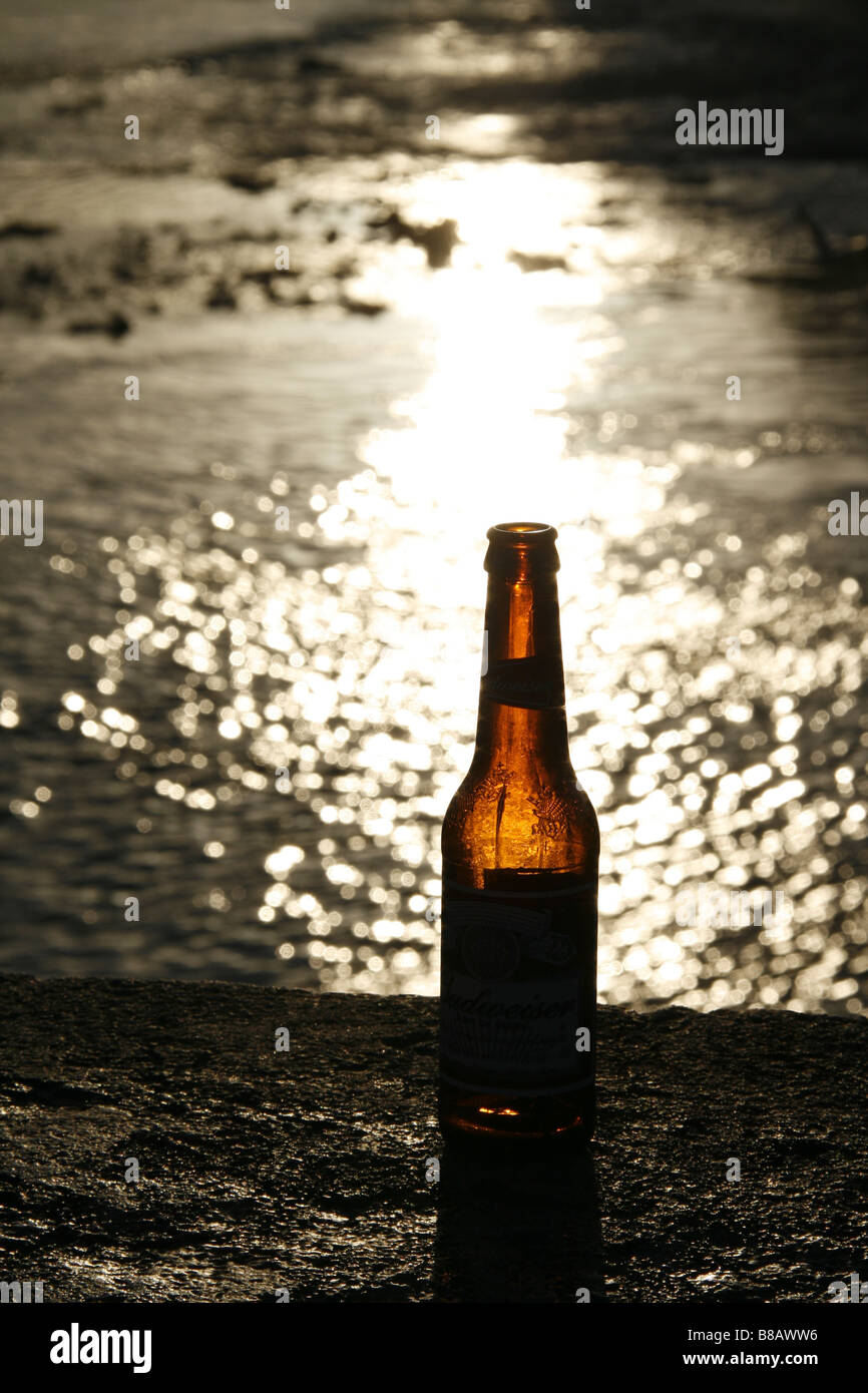 one empty beer bottle on wall by river at sunset Stock Photo - Alamy